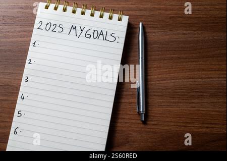 Notepad with text 2025 Priorities, on wooden surface. Priorities and ...