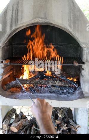 Hand keeps fire going in a grill with fiery flames - an empty fire ...