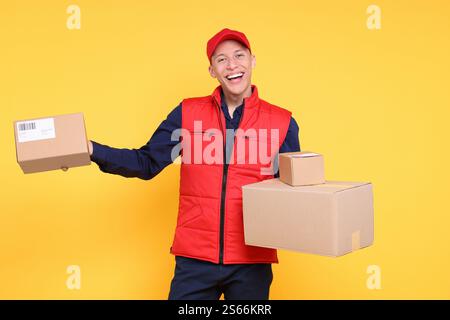 Happy postman with parcels on yellow background Stock Photo - Alamy