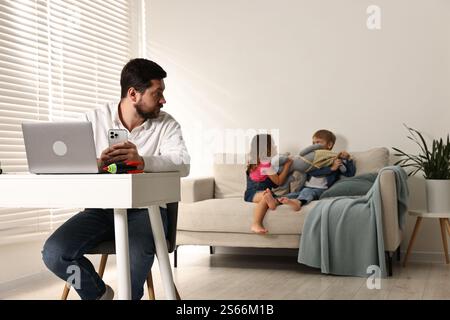 Naughty children disturbing their overwhelmed father at table with ...