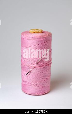 One single pink thread spool with needle on white background Stock ...
