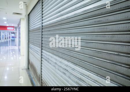 Metal roller shutters rolled down infront of shops inside an old mall ...