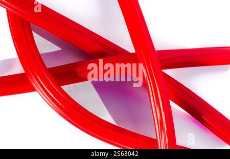 Multiple intertwined red licorice sticks creating a pattern on white ...