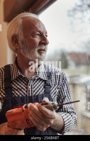 Elderly man holding an electric screwdriver Stock Photo - Alamy