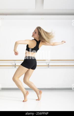 Young and graceful female ballet dancer in motion isolated on dark ...