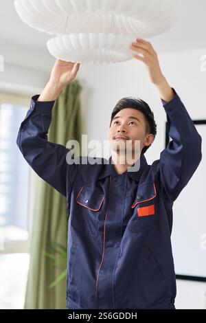technician is fixing a light bulb at the ceiling Stock Photo - Alamy