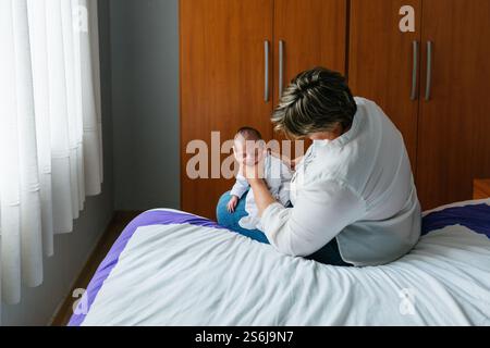 Portrait of a beautiful mother with her 2 month old baby in the bedroom ...
