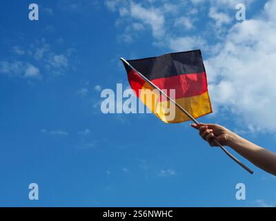 German flag on the flagstaff waving against clear blue sky at sunnt day ...