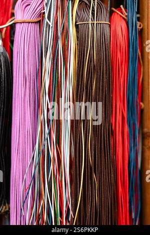 A bunch of colorful cords are hanging from a rack. The cords are of ...