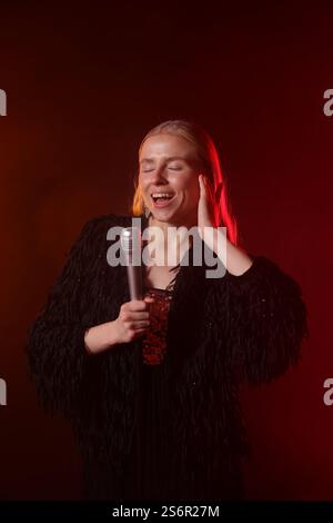 Beautiful singer performing on dark background with color light Stock ...