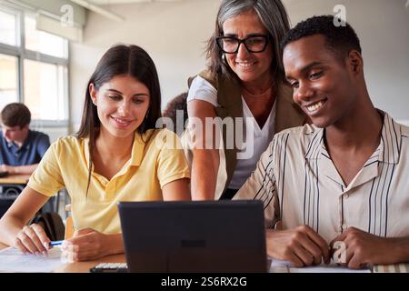 Two university students with female teacher mentor study while sitting ...