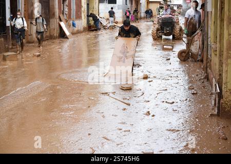 People use flood water to remove mud from clothings at a village hit by ...