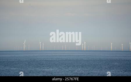 tens of tall wind turbines of an offshore wind farm, in action, Gwynt y ...