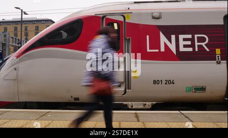 A commuter walks past an LNER Azuma train at Kings Cross station ...