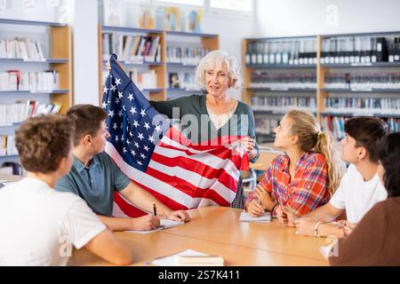 Mature female teacher working with schoolgirls and schoolboys, holding ...