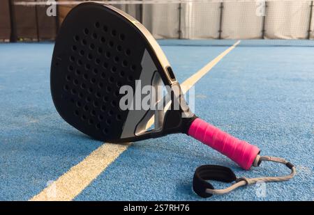 Photo of an orange padel racket and a ball on the ground of a blue ...