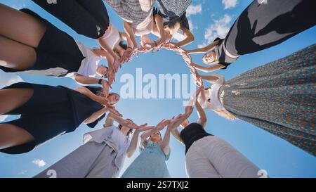 Group of friends forming a circle joining hands together outdoors in a ...