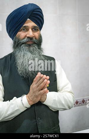 Posed portrait of a Sikh devotee in blue clothing with a spear and a ...