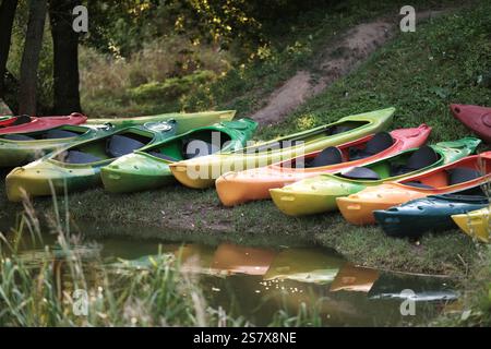 Many canoes of different colors on the river bank before training ...