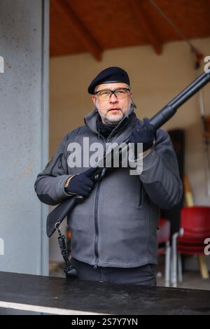 An instructor of shooting in a beret at a shooting range shows where to ...