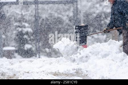 A man is shoveling snow with a snowplow. The snow is falling and the ...