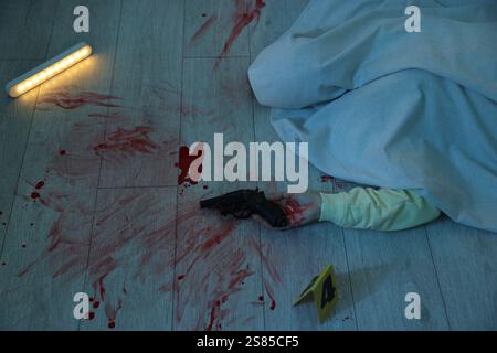 The body of a victim is covered with a blanket as police officers ...