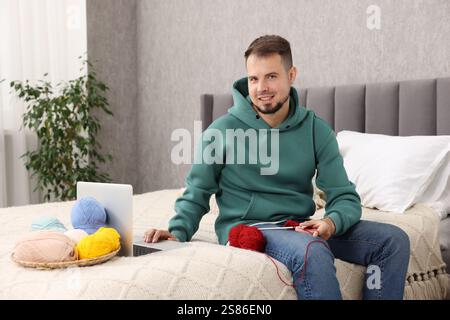 Man learning to knit with online course on bed at home Stock Photo - Alamy
