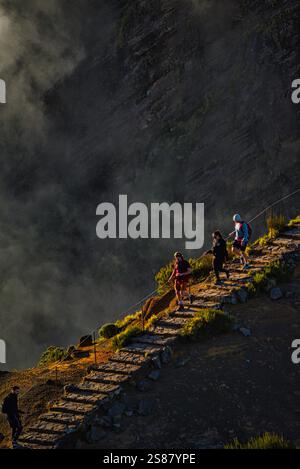 Hikers on trail pathway along jagged volcanic cliffs on Pico Areeiro ...