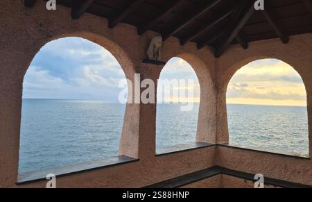 Beautiful coastal view through arched windows with sun setting over the ...