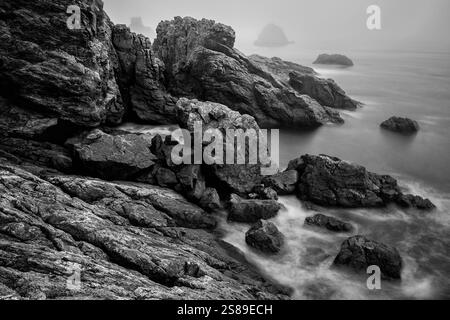 Rugged granite sea cliffs, with blurred long exposure sea, on the South ...