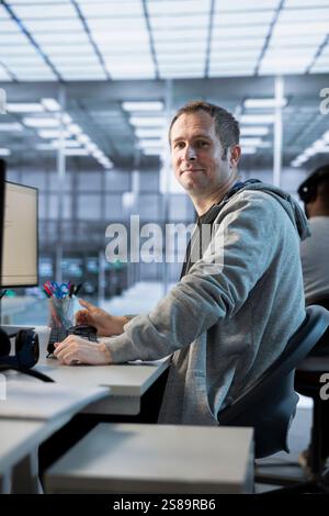 Portrait of smiling engineer inspecting server rows in data center ...
