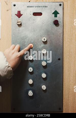 A small child's female hand presses the button in the elevator to go to ...