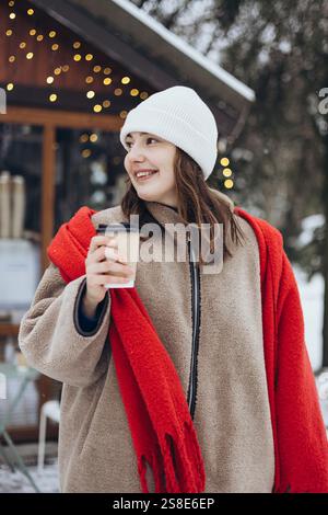 A woman holds a red cup while standing by a Christmas tree Stock Photo ...