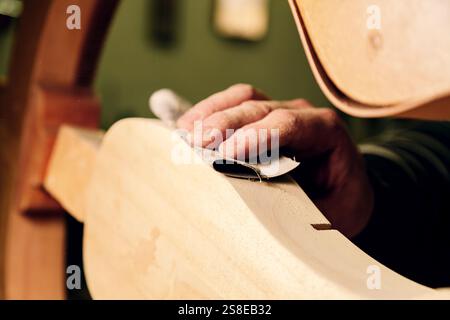 Wood artisan sanding guitar body, creating musical instrument in ...