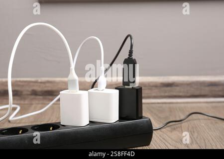 USB adapters with charge cables in power strip on floor, closeup Stock ...