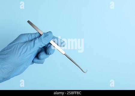 Doctor with surgical hook on light blue background, top view. Space for ...