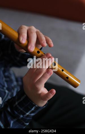A child playing a wooden reed pipe, showcasing skill and concentration ...