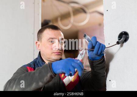 Professional builder engaged in electrical installation work at indoors ...