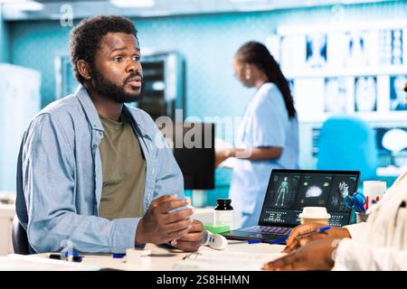 Black male patient bringing x ray test results to medic for scan ...