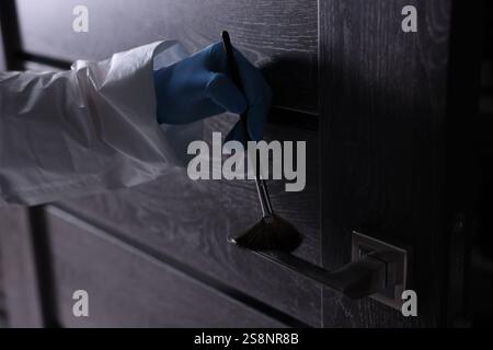 Forensic expert taking fingerprints with brush from gun at table ...