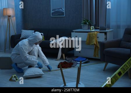 Forensic expert with measuring tape working at crime scene in messy ...