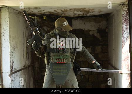 A tactical operator dressed in military gear and a cap stands inside an ...
