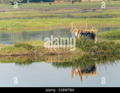 Small straw hut or shelter to provide shade on small island in the calm ...