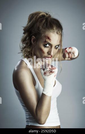 Aggressive female fighter with bruises, wearing a bloody bandage around ...