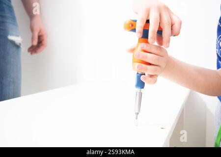 Man controlling as his son's hands screwing the screws into white ...