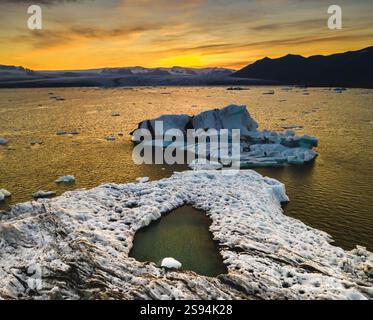 A stunning sunset over icy waters, with floating icebergs and a ...