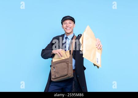 Happy postman with bag giving envelopes on light blue background Stock ...