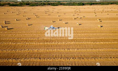 Above view sideways on tractor as pulling round baler, machine that ...