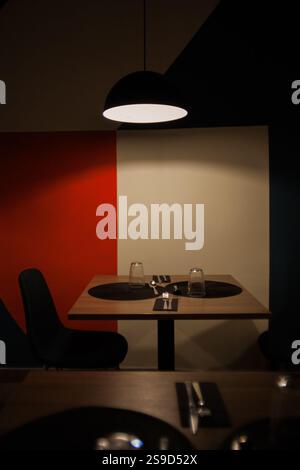 Dimly lit restaurant table place setting for two with wine glasses ...