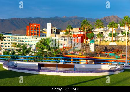 Lush palm trees and rugged mountains under a clear blue sky in a desert ...